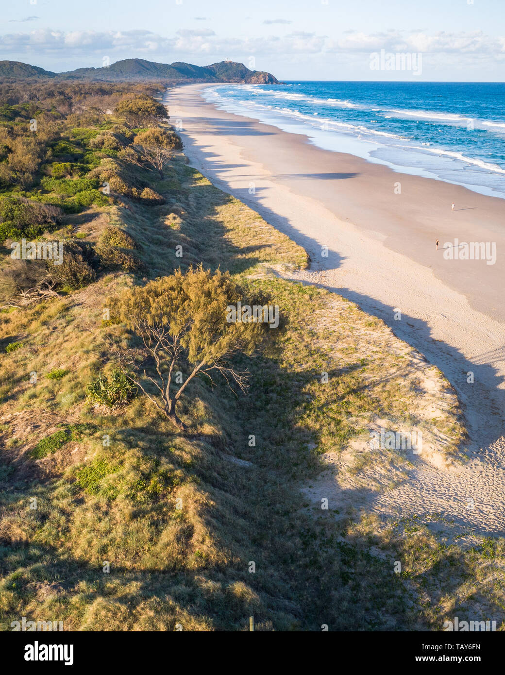 Aerial shot at sunrise over the ocean, sand beach with swimmers and ...