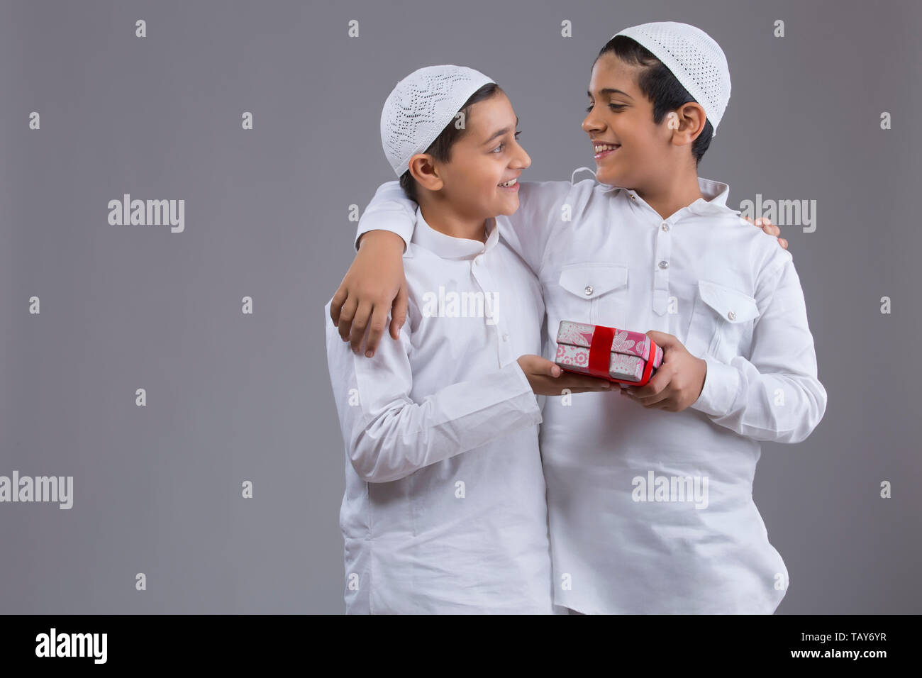 portrait of brothers smiling at each other with a present in their hand ...