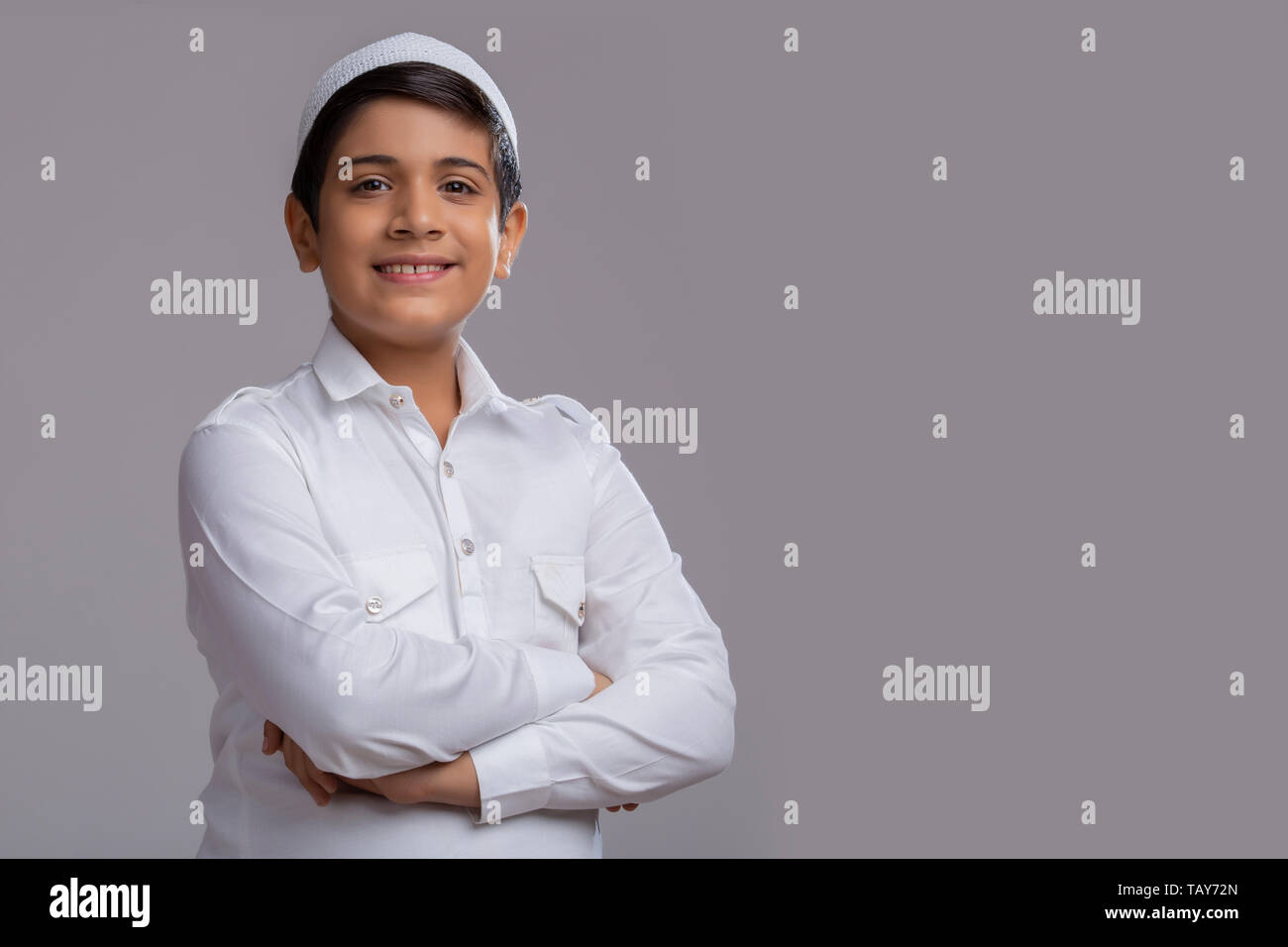 young Muslim boy wearing cap folding hands and smiling Stock Photo - Alamy