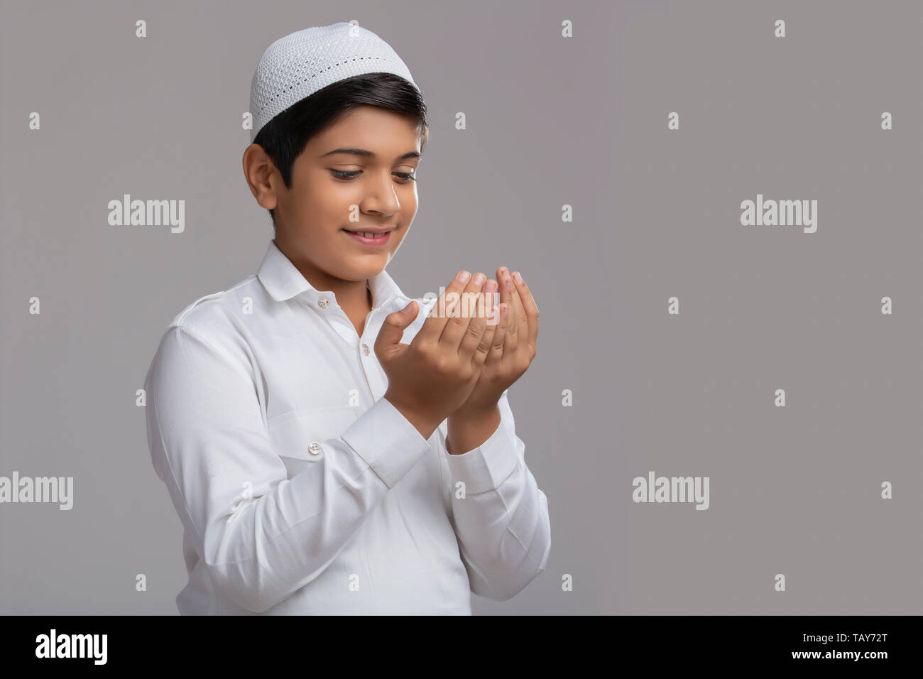 young Muslim boy wearing cap praying and smiling Stock Photo - Alamy