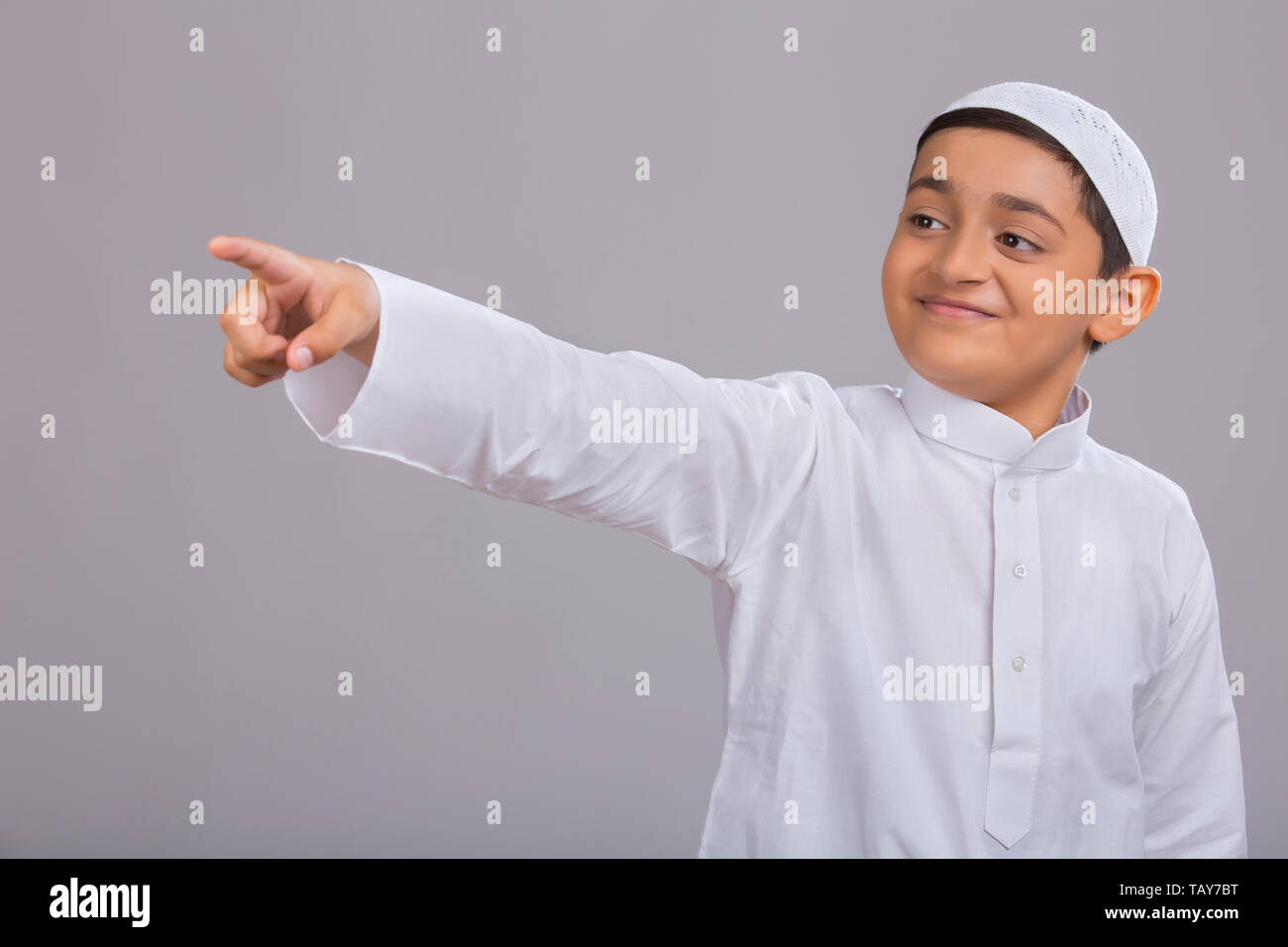 Young Muslim boy wearing cap looking away, smiling and pointing Stock ...