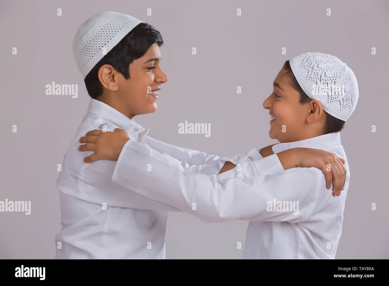 Young Muslim boys with caps looking at each other and smiling Stock ...