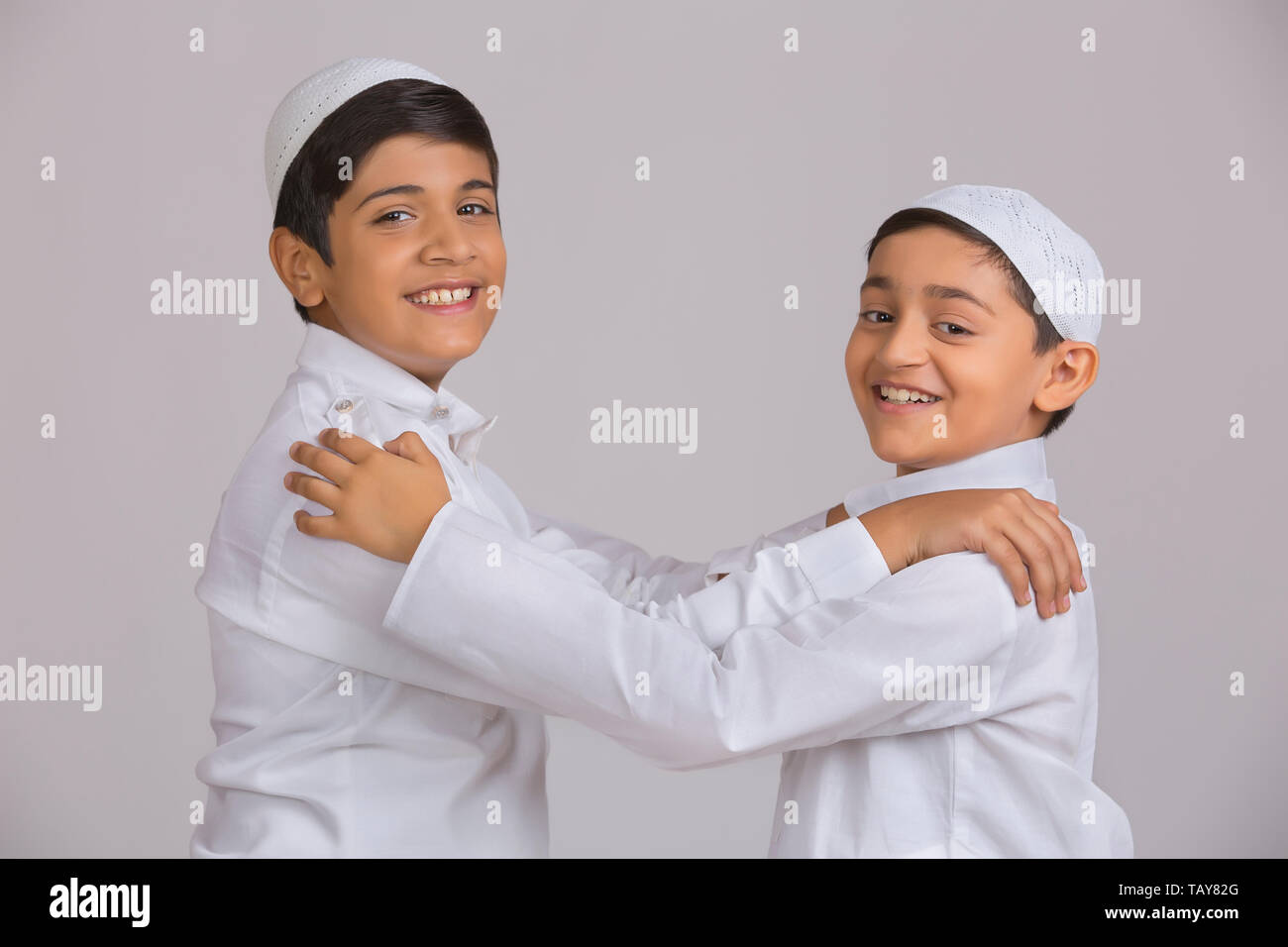 Young Muslim boys with caps smiling and keeping hands on each other ...