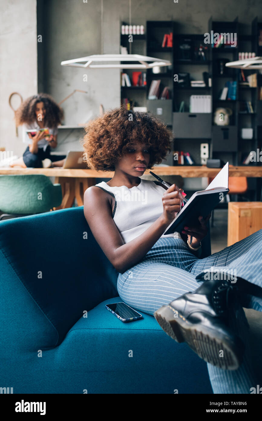 two young multiracial women writing and working in modern coworking ...