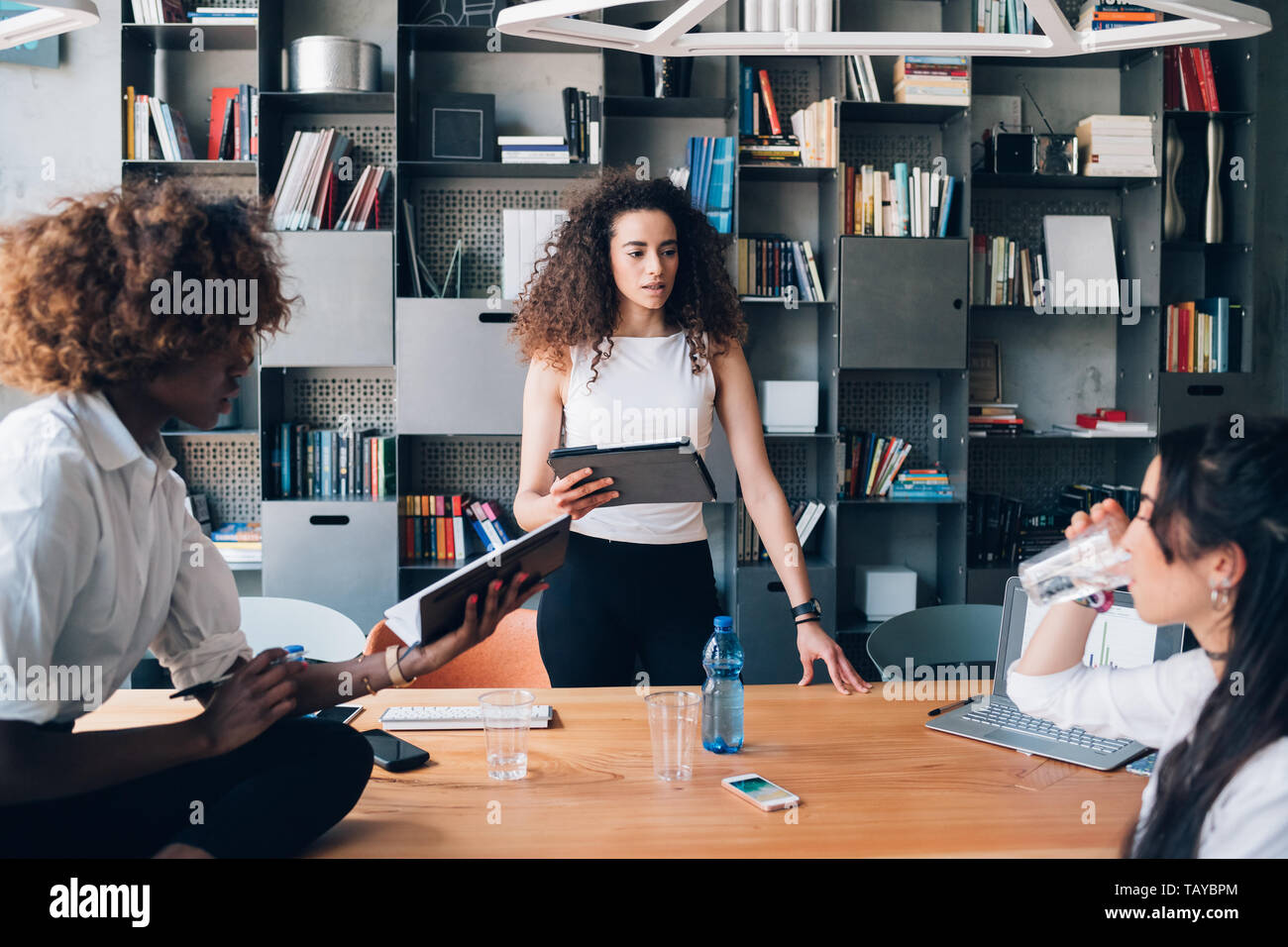 three young multicultural students discussing project in coworking ...
