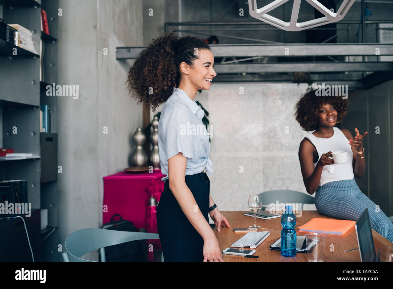 two young multiracial women having informal meeting in modern loft ...