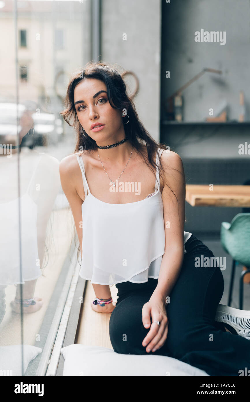 young caucasian woman lean on bench with crossed legs looking camera ...