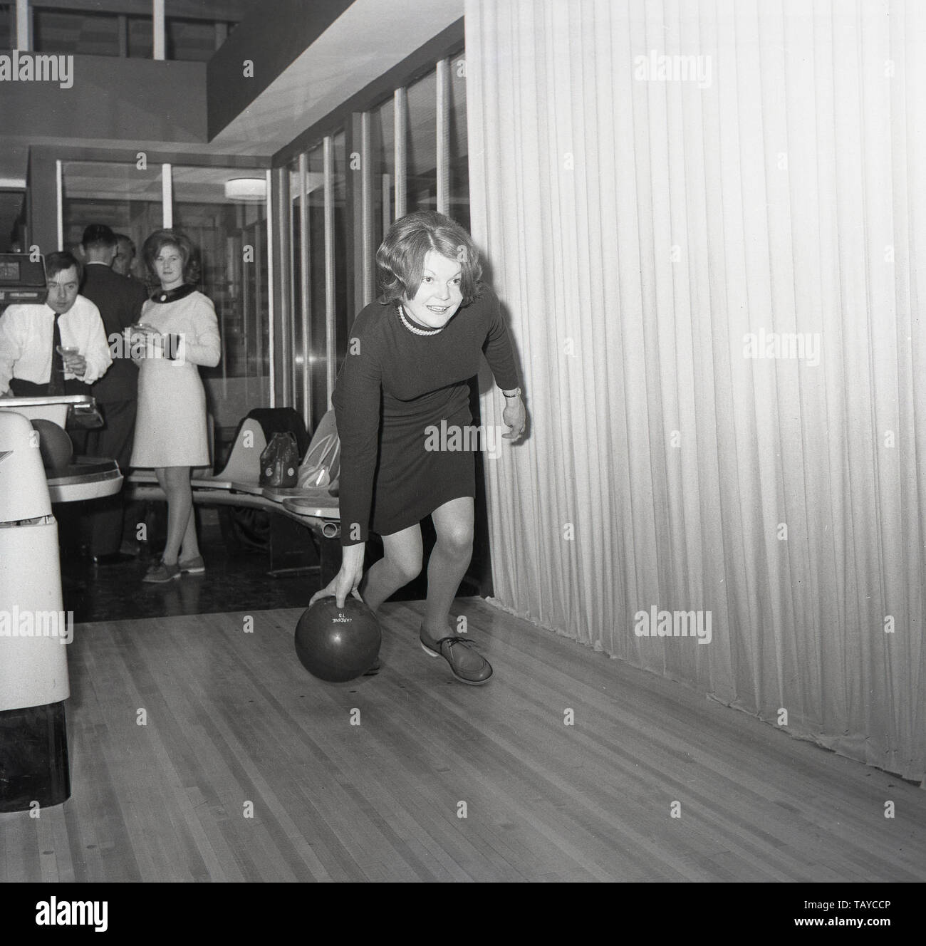 1967, historical, at a bowling alley, a lady about to throw a heavy ...