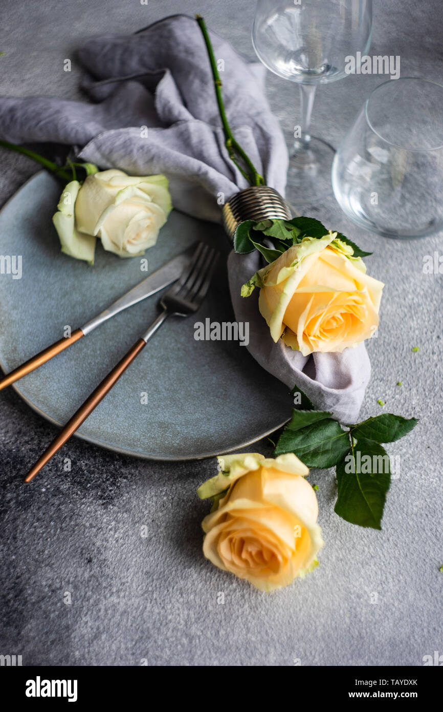 Festive table setting with beautiful roses, modern plates and cutlery ...