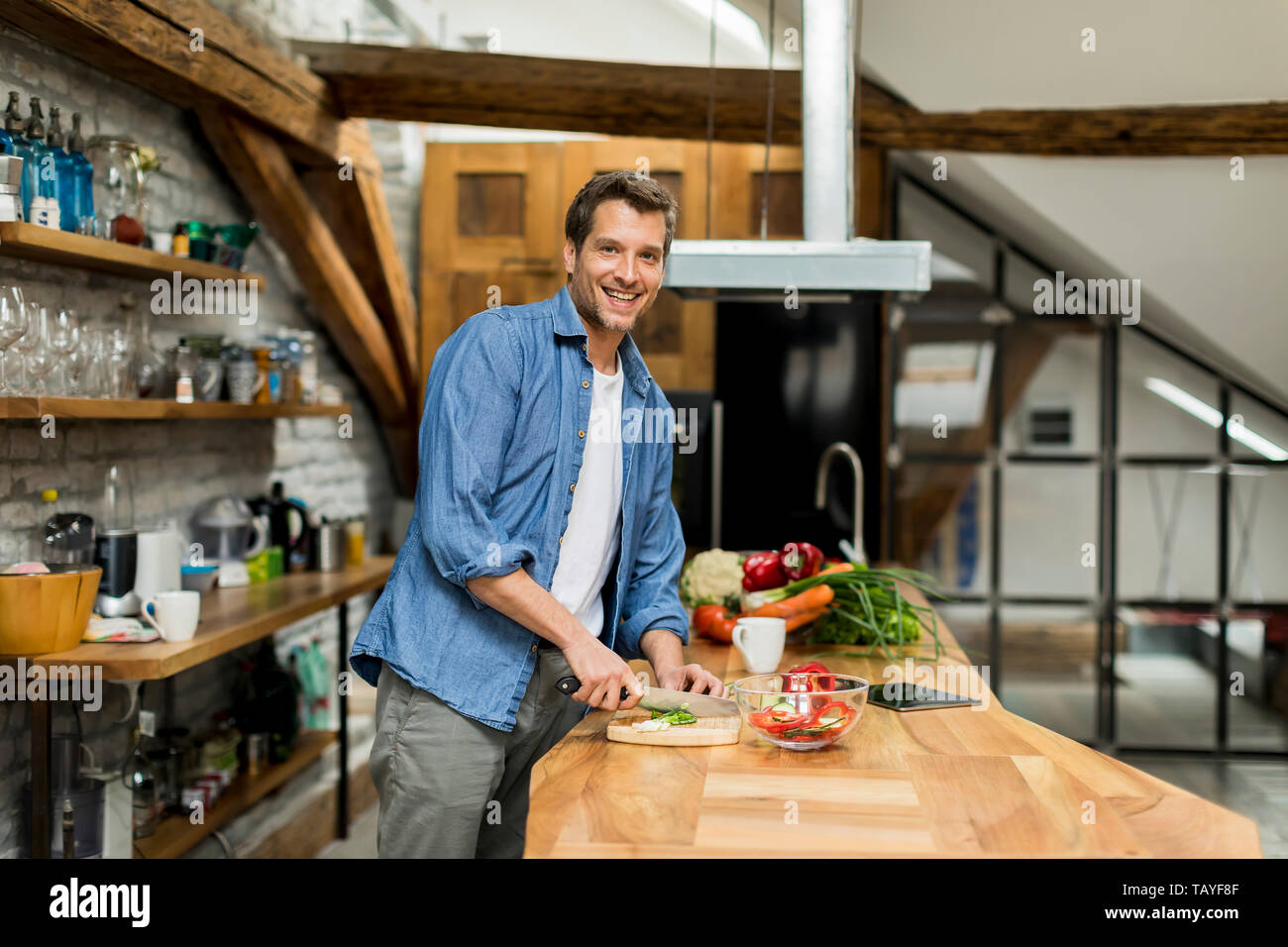 Happy handsome man cooking in rustic kitchen at home Stock Photo - Alamy