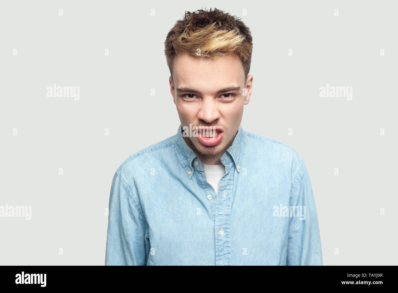Portrait of angry aggressive handsome young man in light blue shirt ...