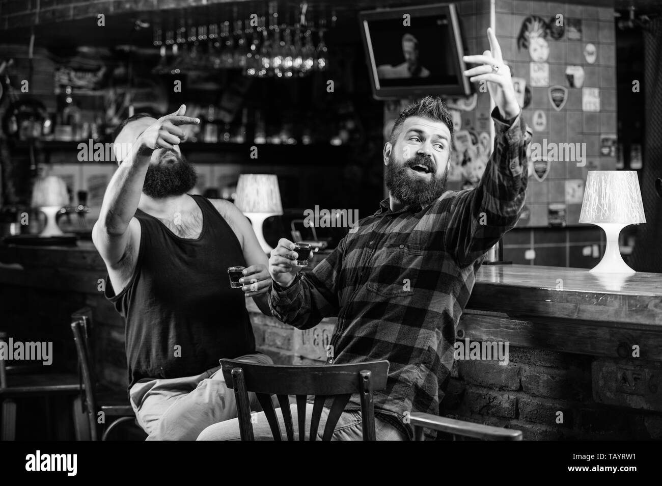 Hipster brutal bearded man drinking alcohol with friend at bar counter ...