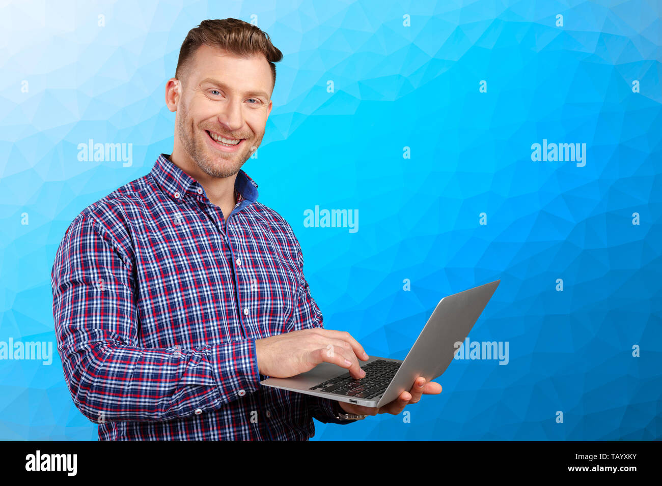 Young man standing, holding laptop computer, working Stock Photo - Alamy