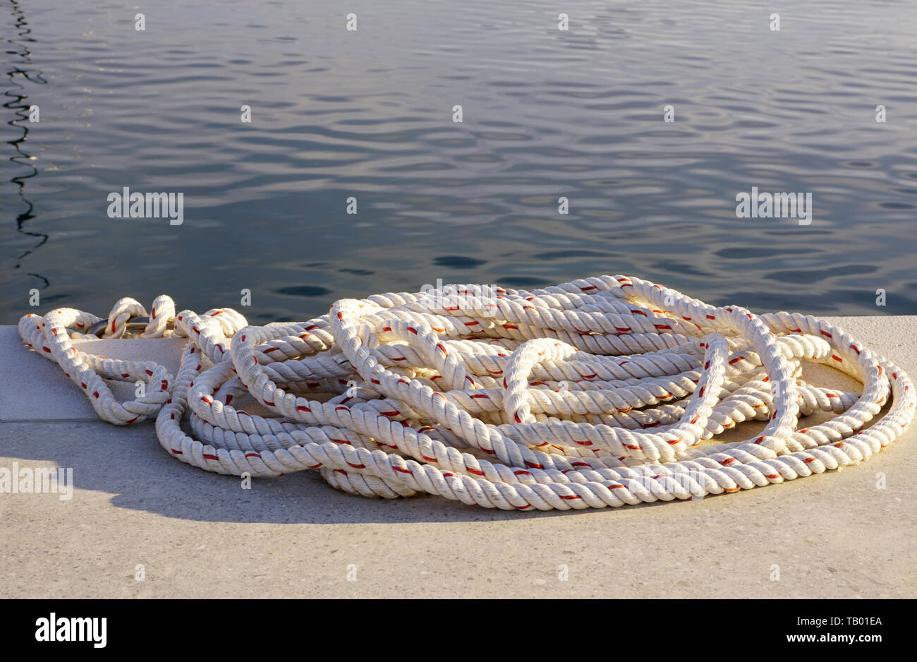 Pile of white rope for mooring boats or yachts on the stone dock by the ...
