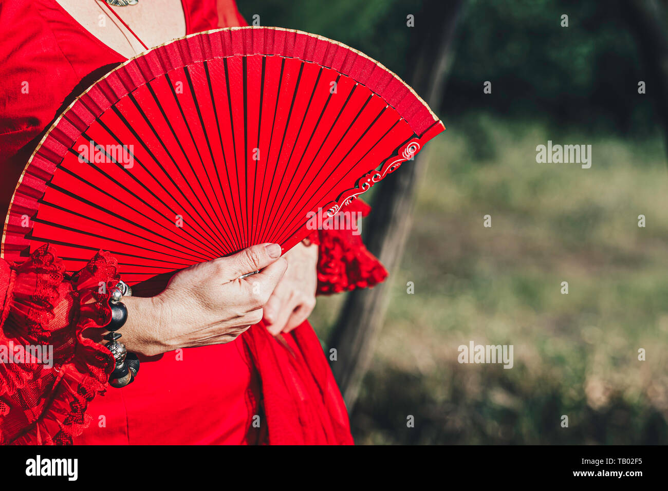 Woman in red dress with hand red open fan and bracelet, headless ...
