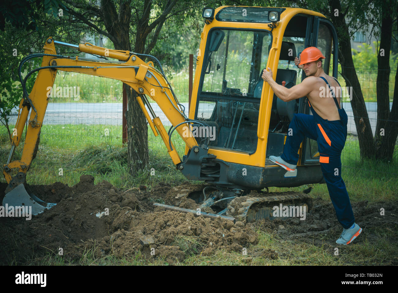 Earthwork concept. Earthwork operator at excavator. Man climb on digger ...