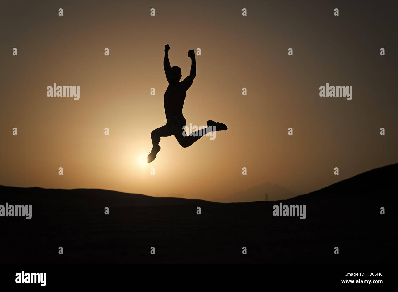 Keep moving. Silhouette man motion jump in front of sunset sky ...