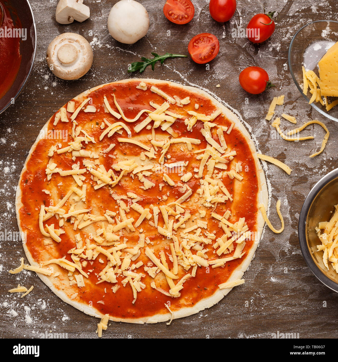 Pizza Base With Grated Cheese And Ingredients Around Stock Photo - Alamy