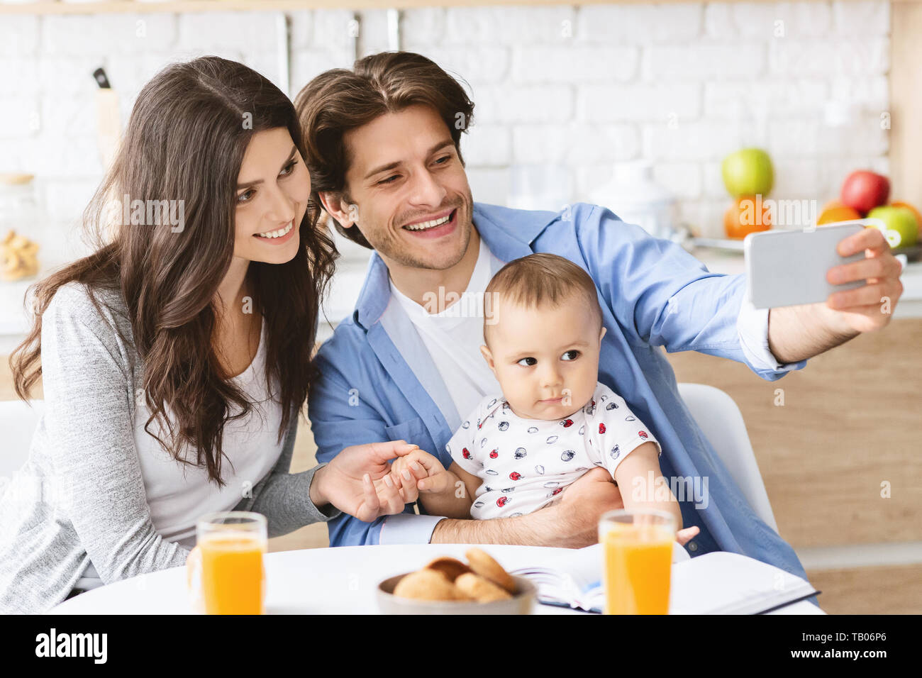Millennial parents photographing themselves with baby son Stock Photo ...