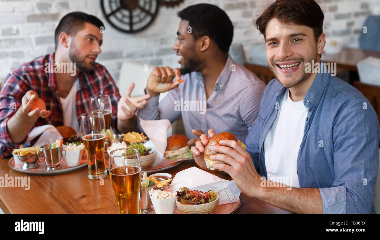 Men Eating Burgers And Drinking Beer In Bar Stock Photo - Alamy
