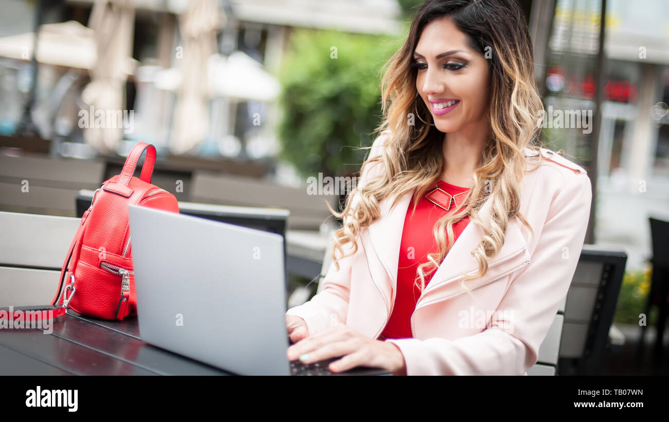 Young woman blogger freelancer in outdoor cafe with computer laptop ...