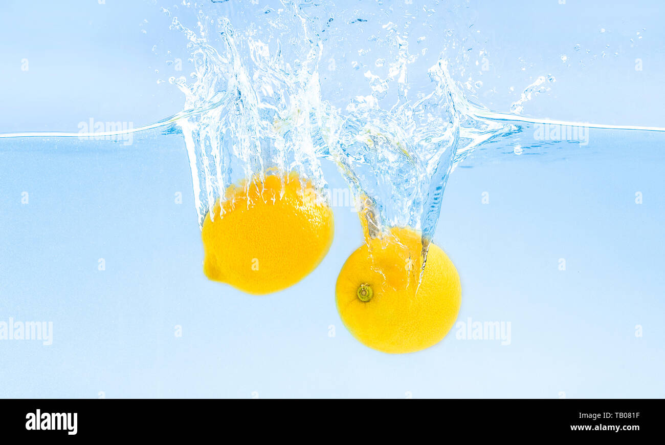 Fresh lemons sinking into water with splash Stock Photo - Alamy