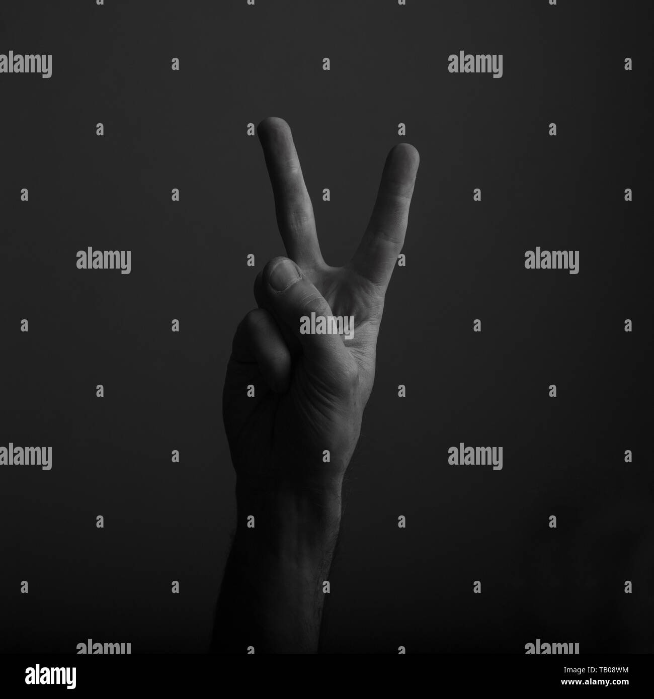 Male hand showing victory V hand sign against a dark background Stock ...