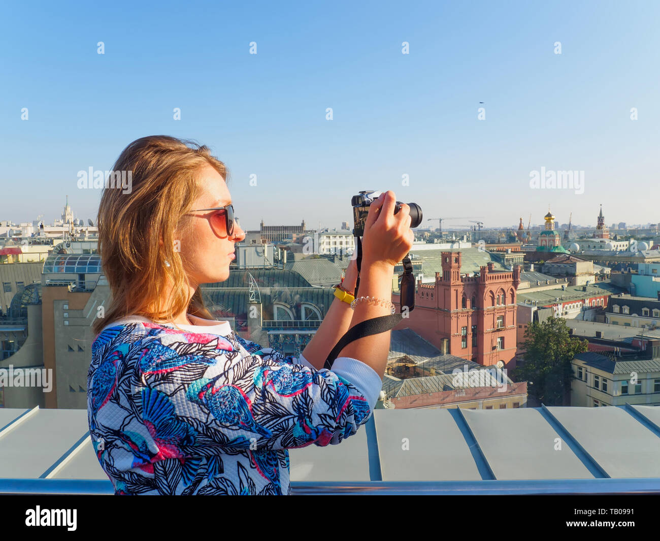 Young beautiful blonde girl taking pictures of the city with a camera ...