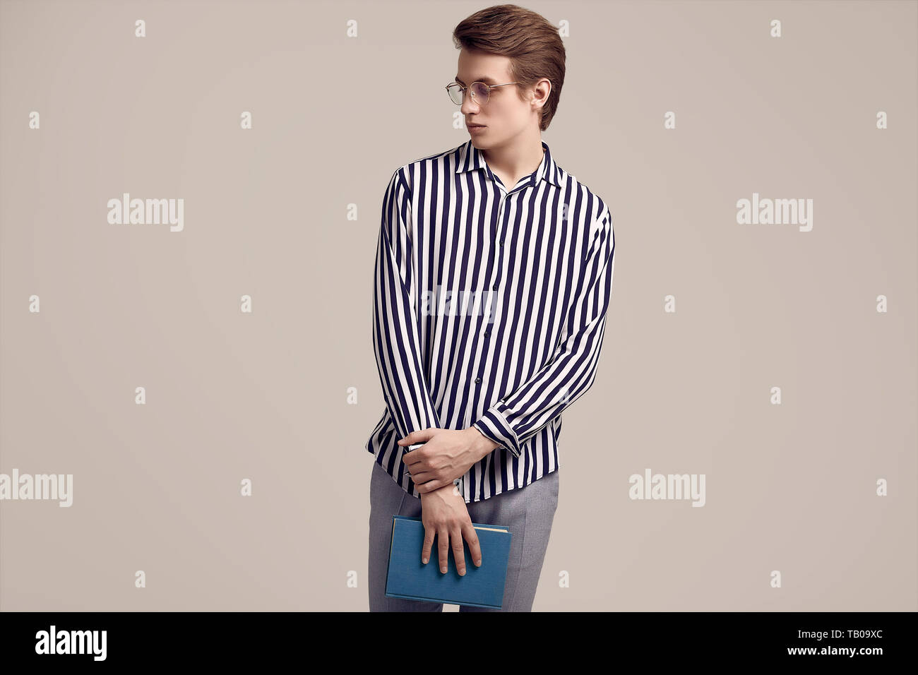 Fashion portrait of young handsome man in striped shirt posing with ...