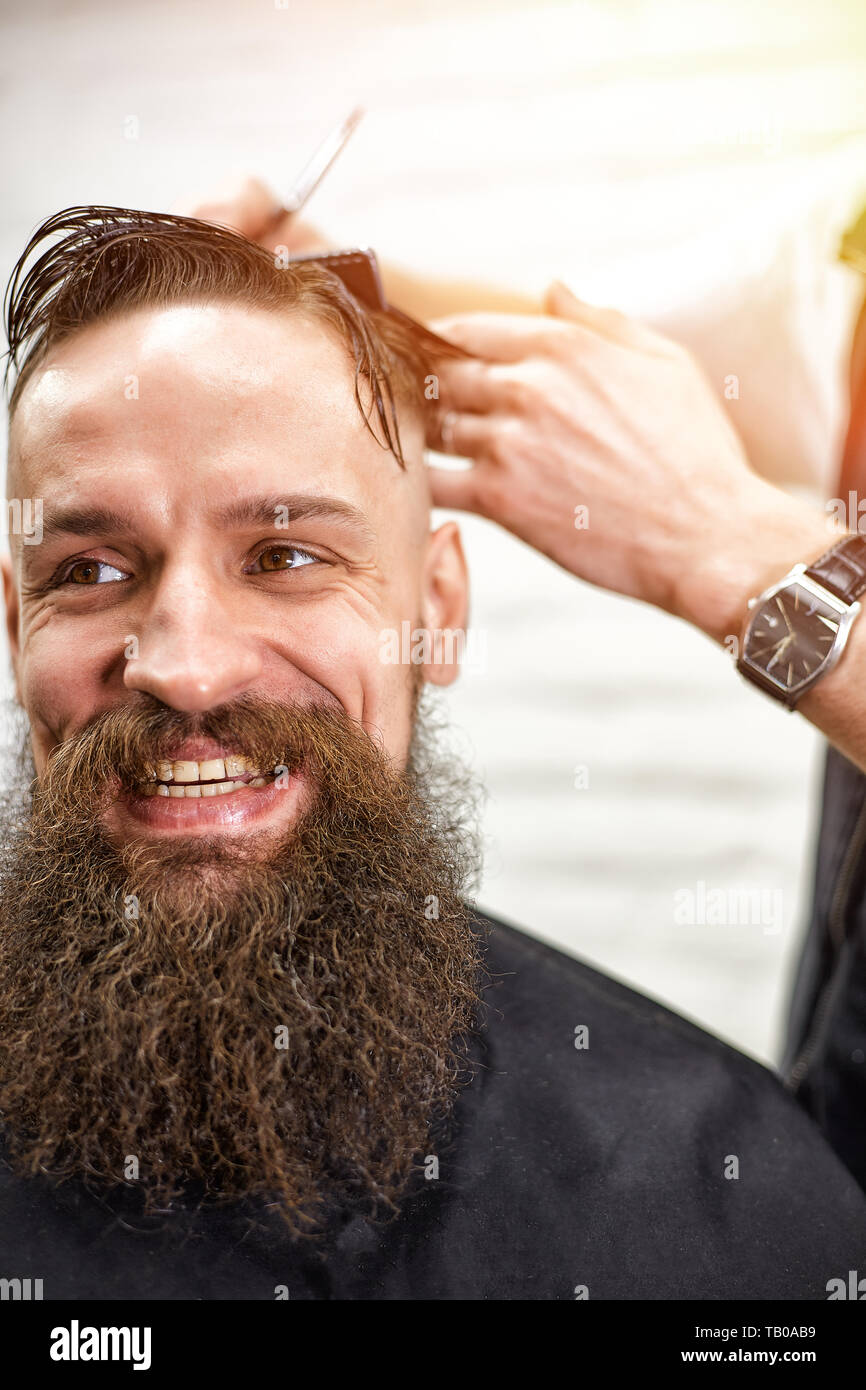 Master cuts hair and beard of men in the barbershop, hairdresser makes ...