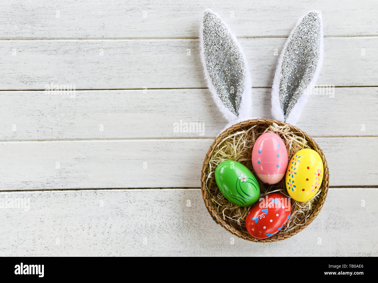Colorful easter eggs and easter bunny ear rabbit in basket nest ...