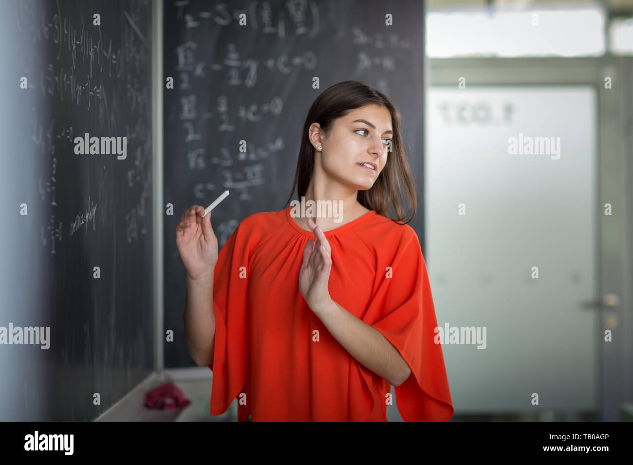 Pretty, young college student writing on the chalkboard/blackboard ...