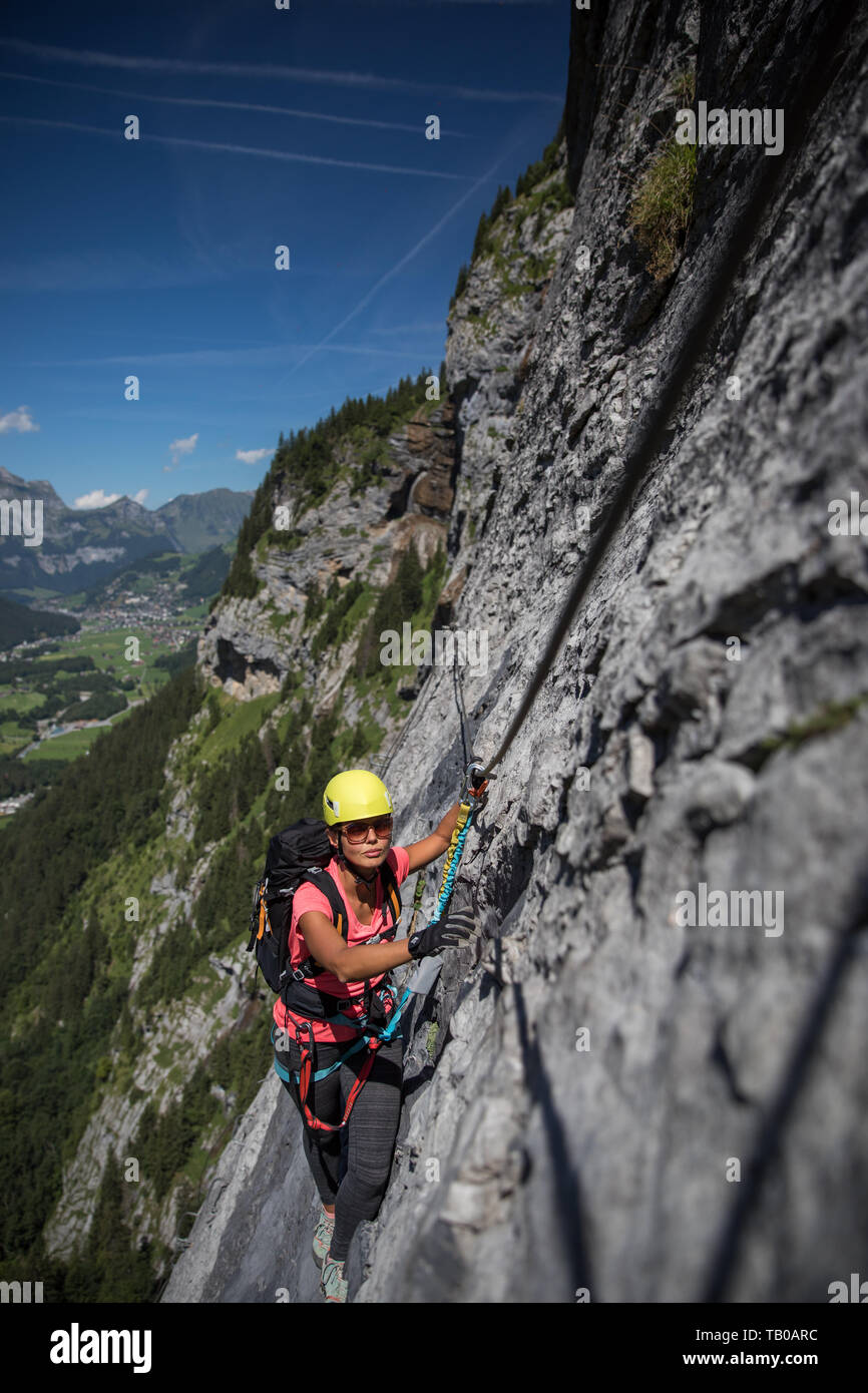 Pretty, female climber on a via ferrata - climbing on a rock in Swiss ...