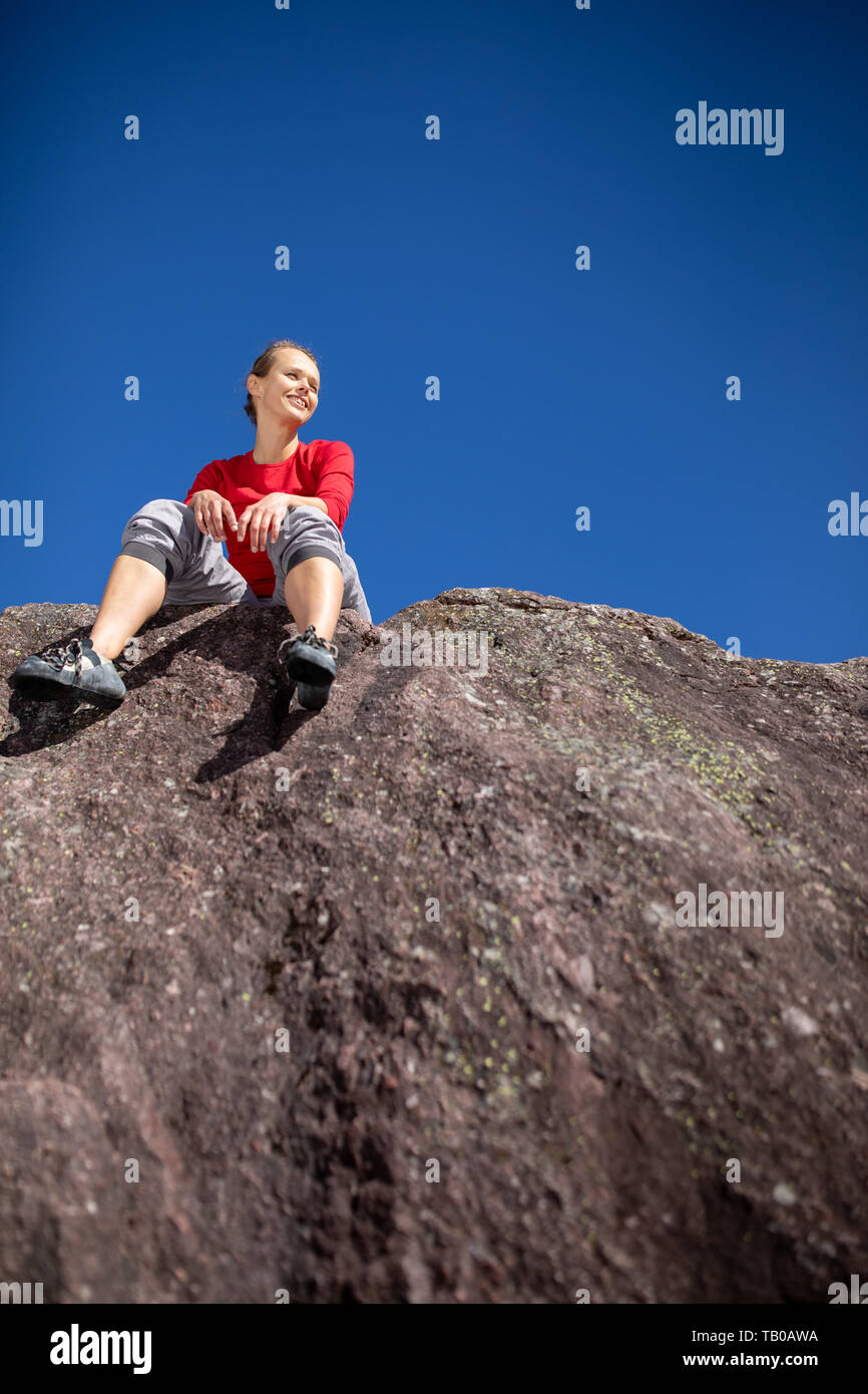 Young female climber atop a natural boulder outdoors, in Swiss Alps ...