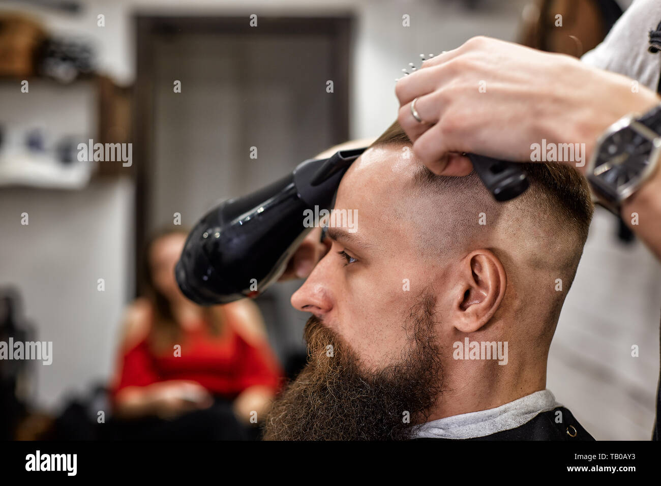 Master cuts hair and beard of men in the barbershop, hairdresser makes ...