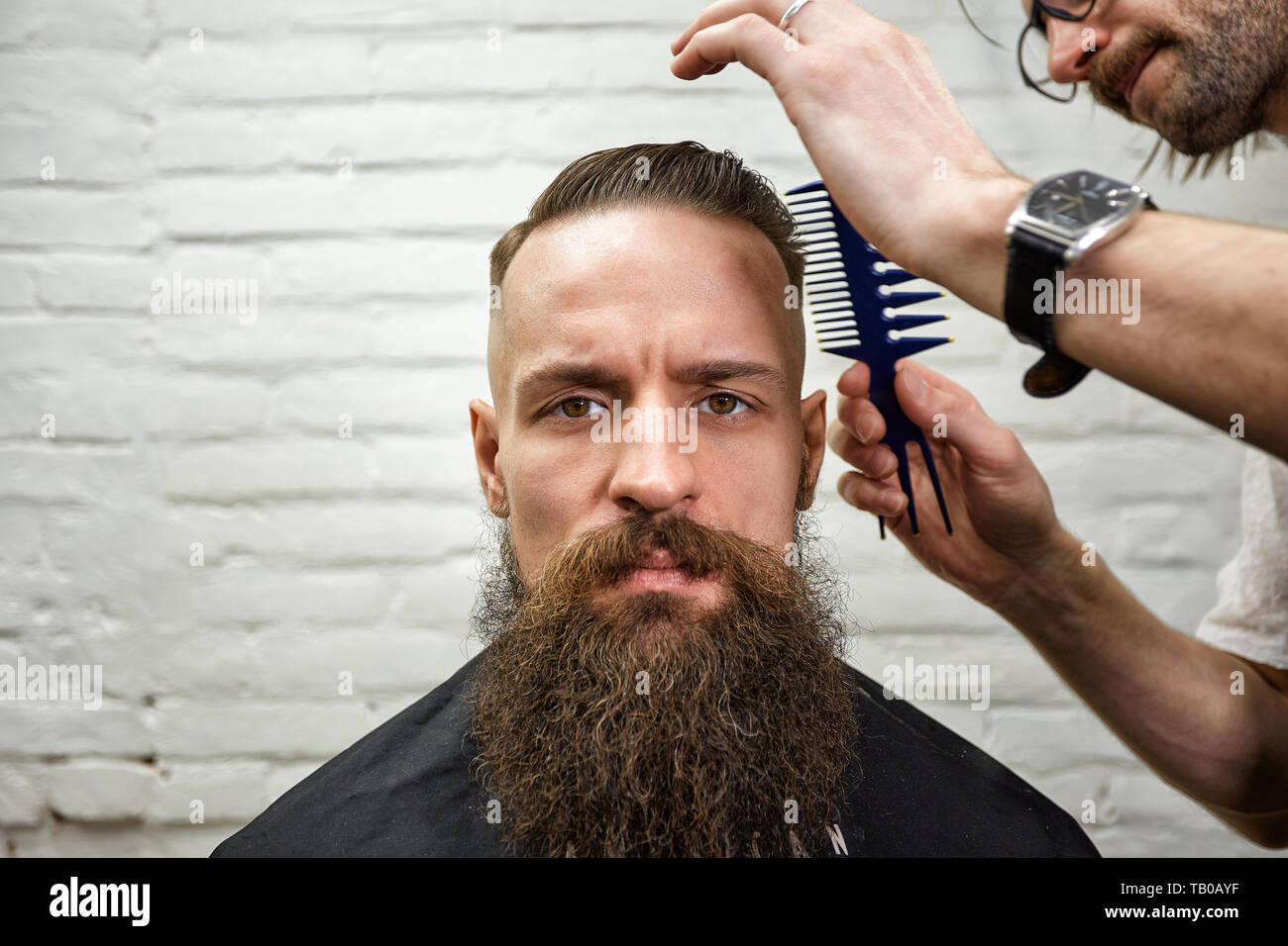 Master cuts hair and beard of men in the barbershop, hairdresser makes ...