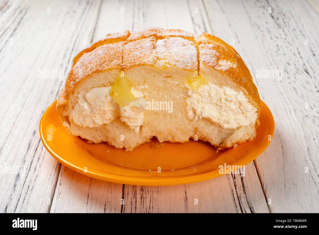 side view bread with cream inside with half eaten on wood table Stock ...