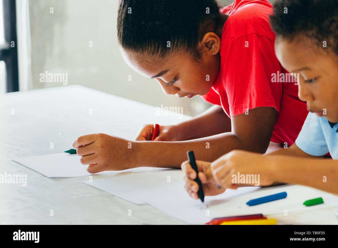 African American kids learning how to draw with crayon on table inside ...