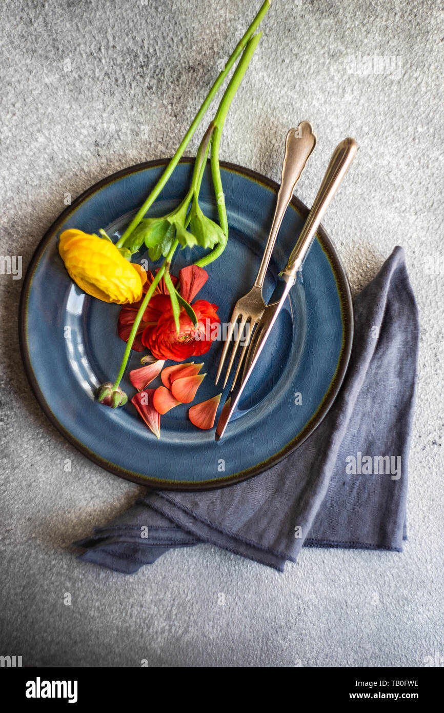 Rustic table setting with ranunculus flowers on concrete background ...