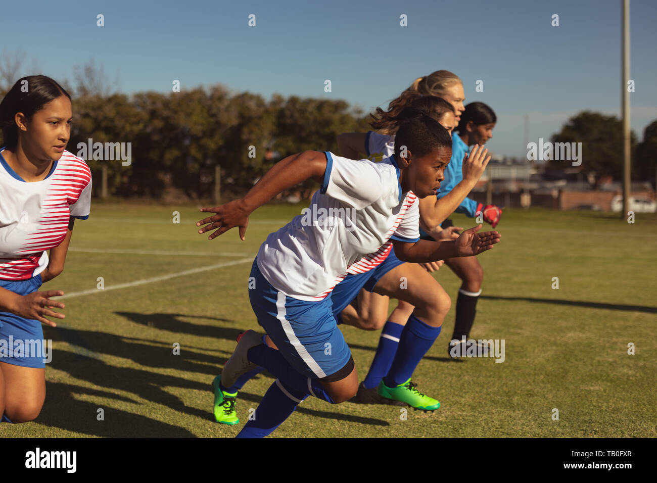Team of female soccer players running at sports field Stock Photo - Alamy