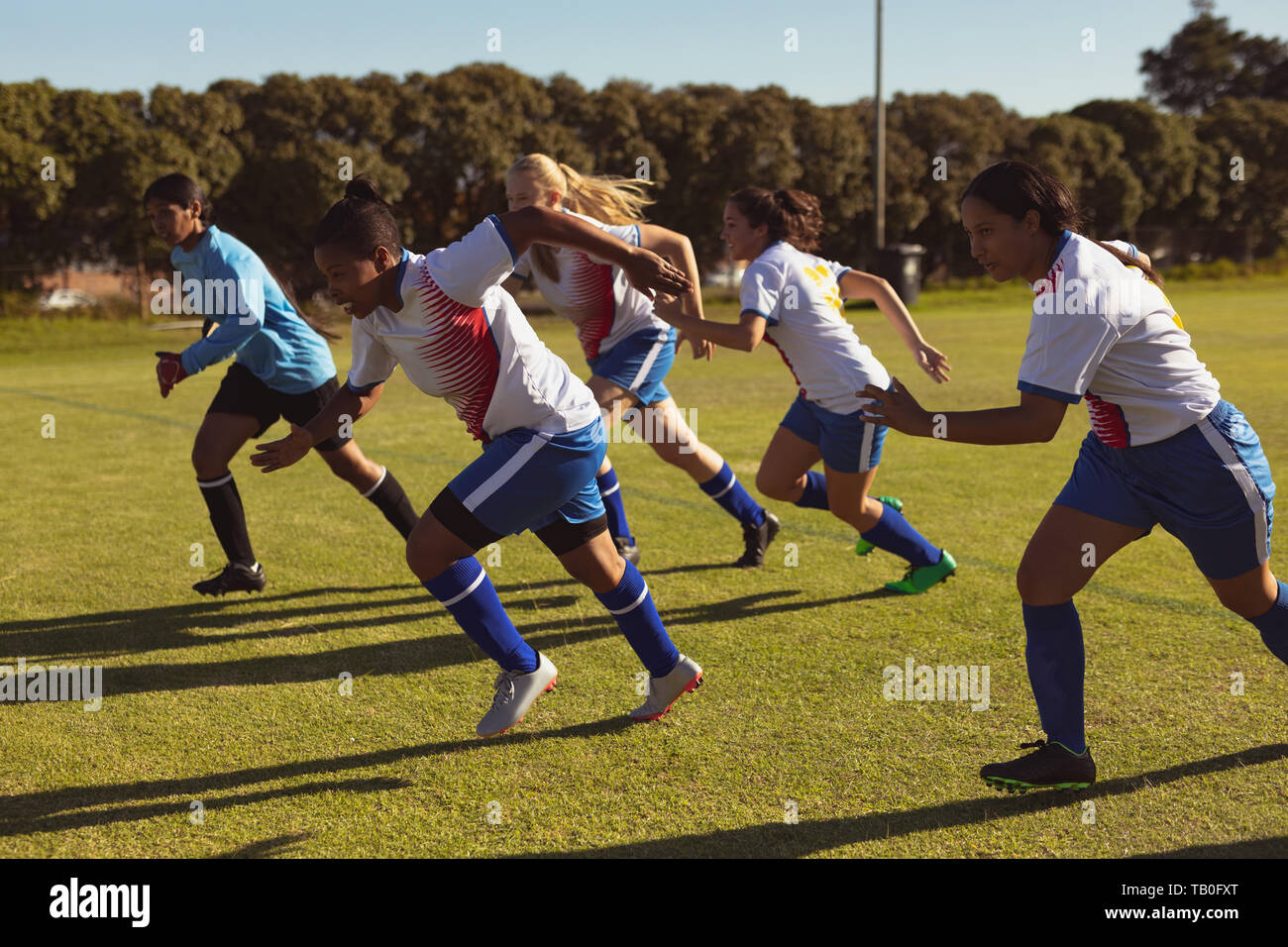 Team of female soccer players running at sports field Stock Photo - Alamy