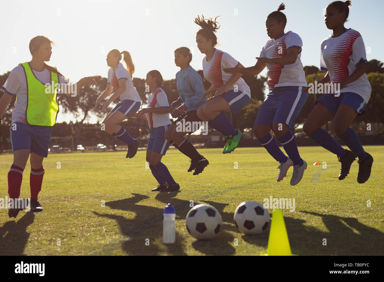 Coach helping female soccer players with jumping exercise Stock Photo ...