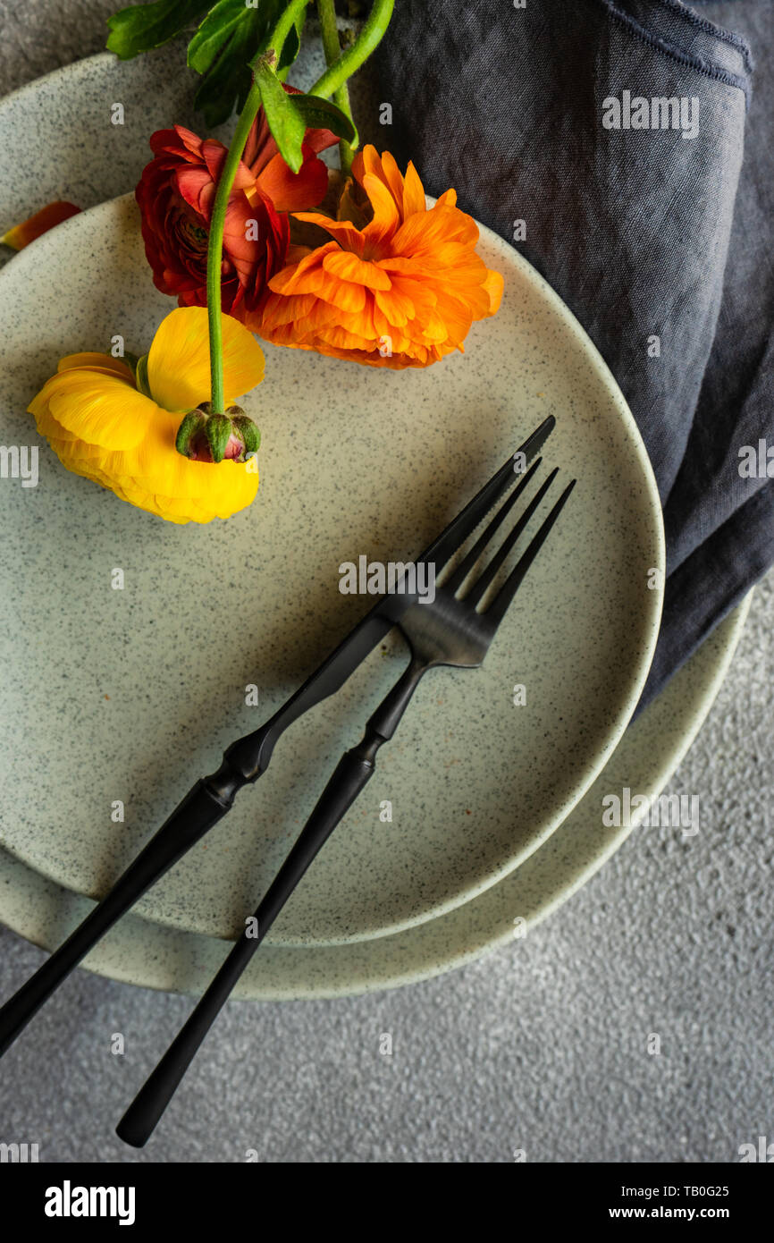 Rustic table setting with ranunculus flowers on concrete background ...