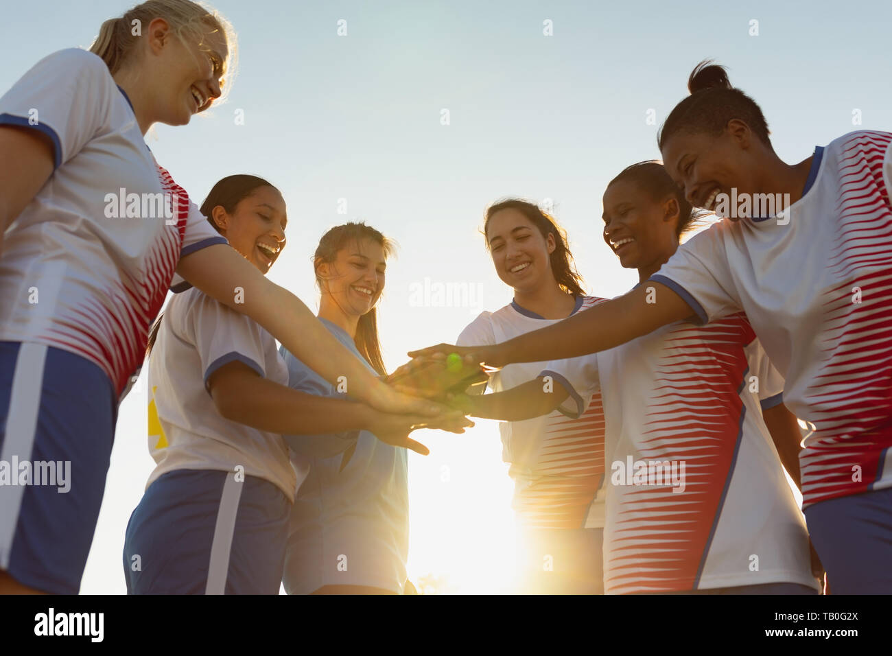 Happy soccer players forming a hand stack on the field on a sunny day ...