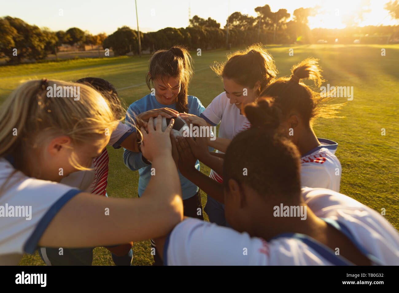 Soccer team cheering in circle with ball Stock Photo - Alamy