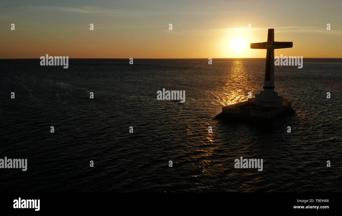 Catholic cross in sunken cemetery in the sea at sunset, aerial drone ...