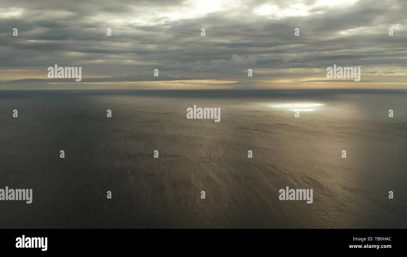 Dramatic sky with clouds over the sea during sunset in cloudy weather, aerial view. Sunset over ...