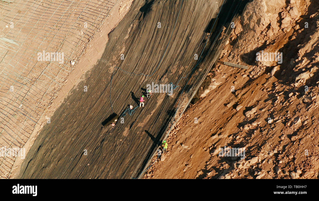 Workers strengthen the slope of the mountain with metal mesh preventing ...