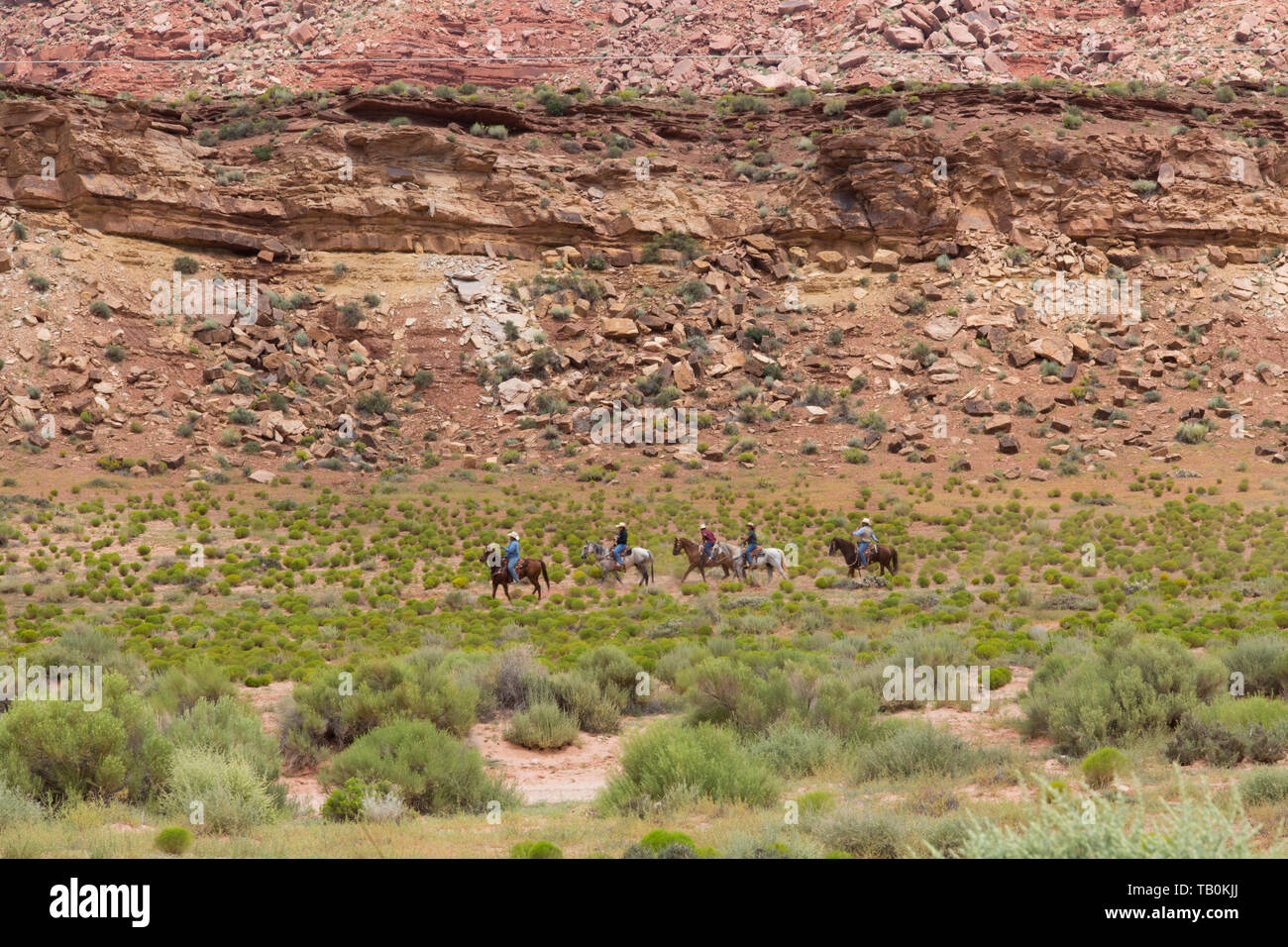 Group of Native American horseback riders in desert, with rock wall in ...