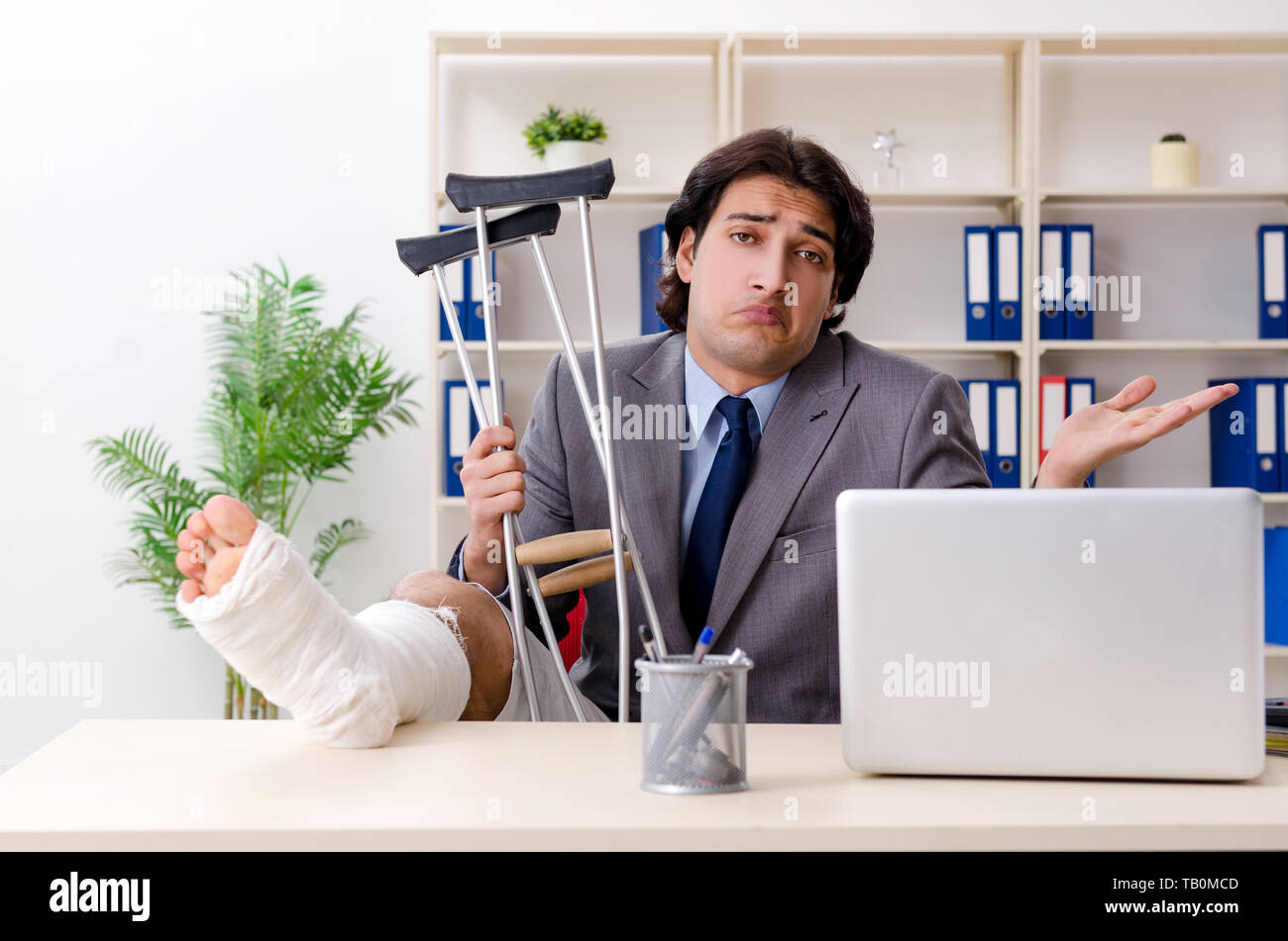 Leg injured employee working in the office Stock Photo - Alamy